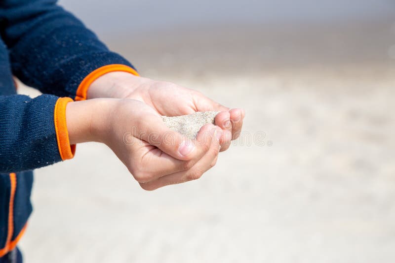 A Little Boy Slowly Lets Sand Flow through His Hands Scattered by the ...