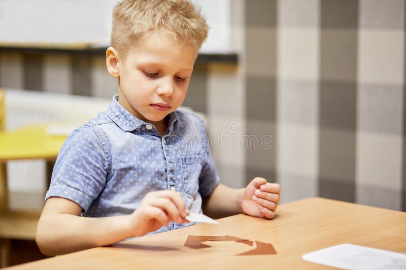 Little Boy Solves Puzzle Sitting at Desk in Stock Photo - Image of ...