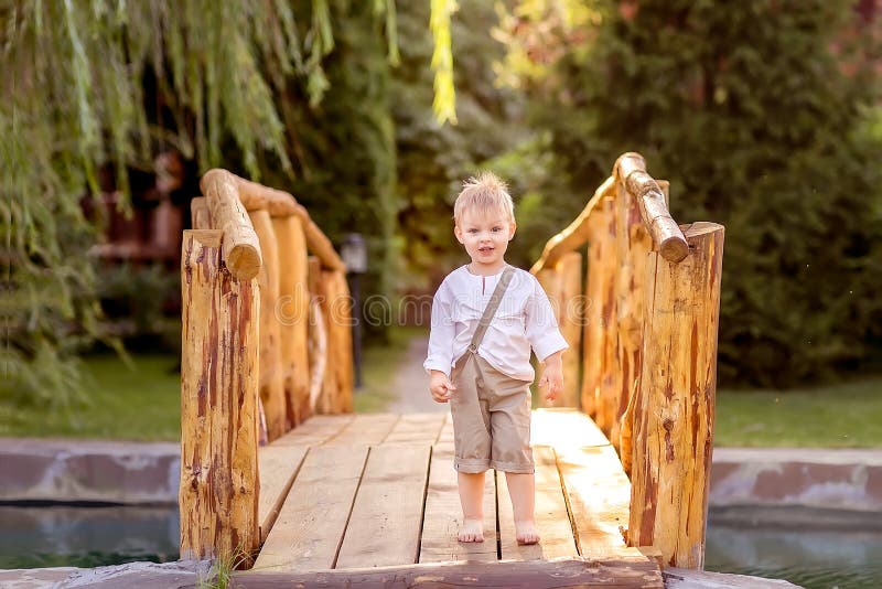 A Little Boy Stands on a Bridge Over the River. Stock Image - Image of ...