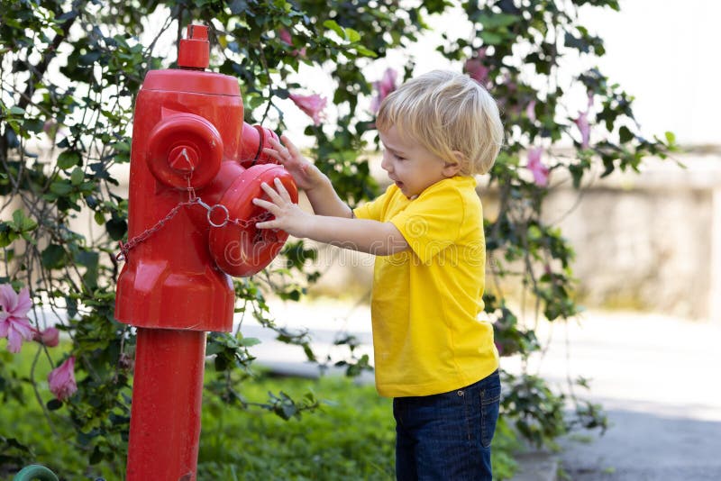 A Little Boy Touching a Red Fire Hydrant Outside Stock Photo - Image of ...