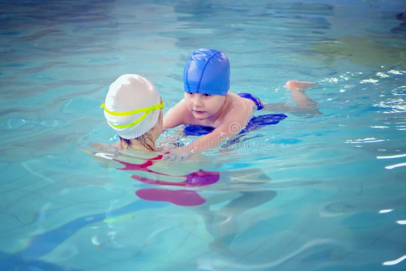 Little Boy Using the Kickboard for Learning To Swim with Trainer in the ...