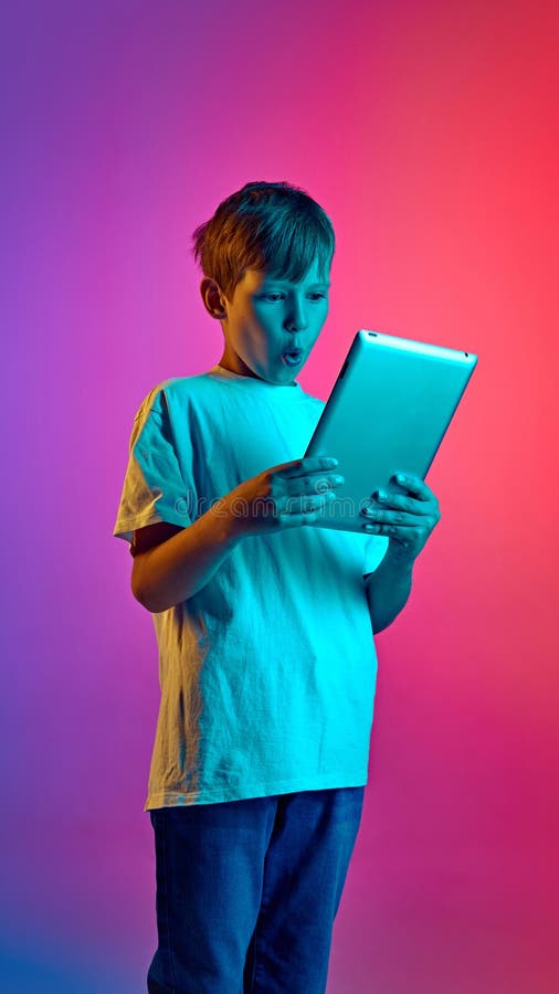 Little Boy Using Tablet and Looks at Screen with Surprise in Neon Light ...