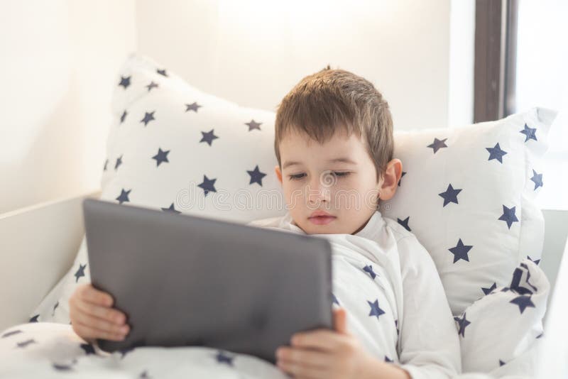 Little Boy Watching Digital Tablet Lying on Bed. Child with Technology ...