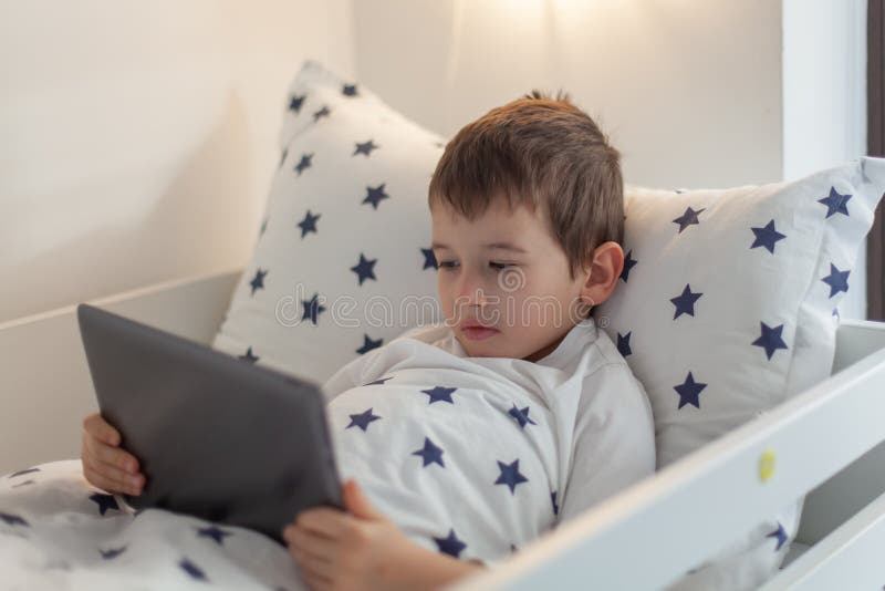 Little Boy Watching Digital Tablet Lying on Bed. Child with Technology ...