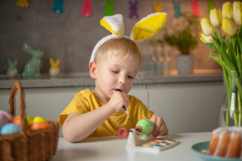 A Little Boy Wearing Bunny Ears Prepares Painted Easter Eggs for Easter ...