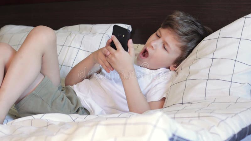 Little Boy Yawning while Looking at Mobile Phone. Stock Video - Video ...