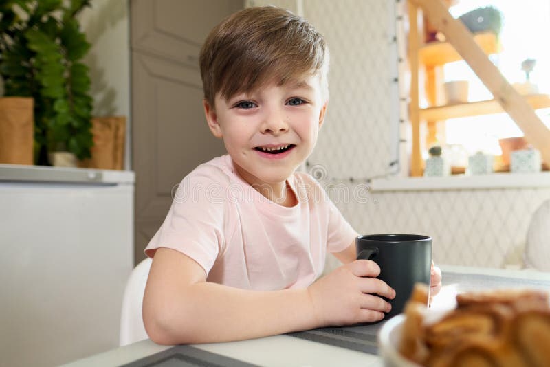 A Little Boy of 7 Years in the Kitchen Drinks Tea from a Gray Cup ...