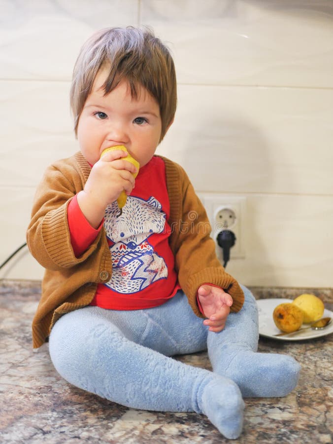 Little Child Eats a Pear. Child Boy Eating Fruits at a High Stoic Stock ...
