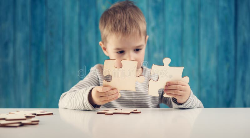 Little Child Holding Puzzle Pieces and Trying To Solve it Stock Photo ...
