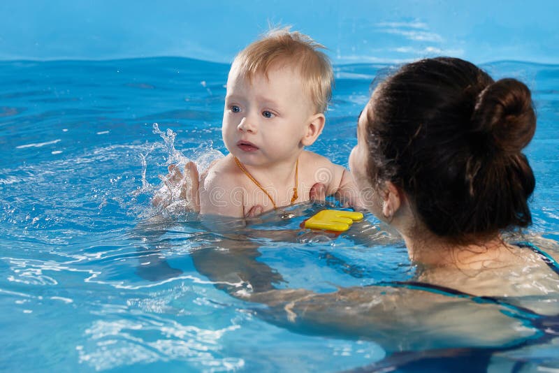 Little Girl Learning To Swim in Indoor Pool with Pool Board and Trainer ...