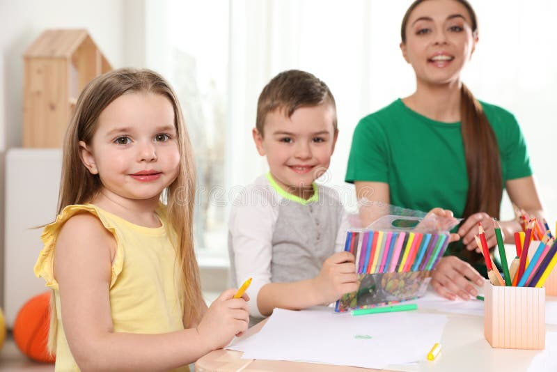 Little Children with Kindergarten Teacher Drawing at Table. Learning ...