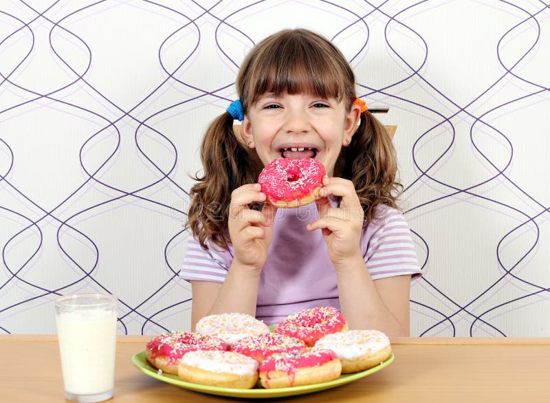 Little girl eating donuts stock photo. Image of cute - 60797414