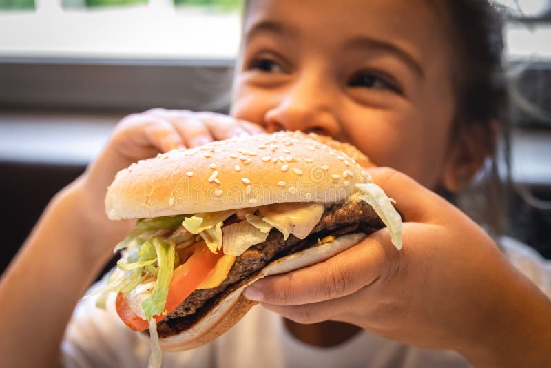 A Little Girl Eats an Appetizing Burger, Close-up. Stock Image - Image ...