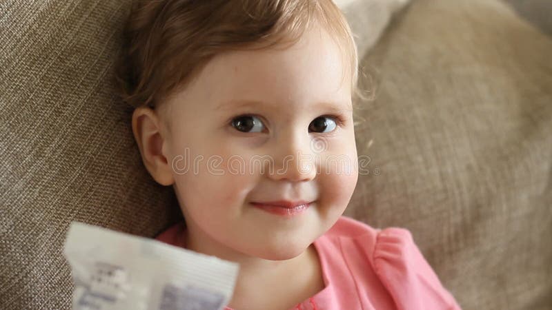 A Little Girl Eats Candy, Smiling and Looking at the Camera Stock ...