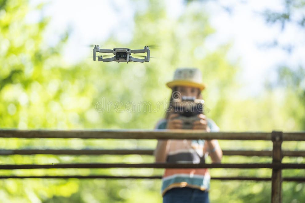 Little Girl Flying a Small Drone in the Park with a Remote Controller ...