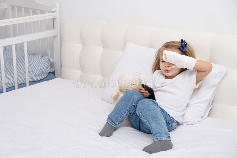 Little Girl with Hand in Cast Sitting in Bed Using Smartphone Stock ...