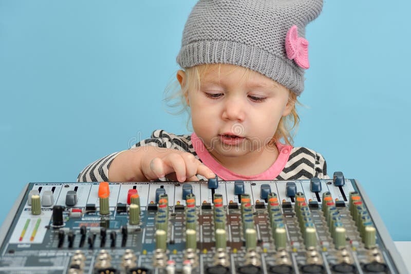 A Little Girl in a Hat Adjusts the Sound with a Mixing Console and ...