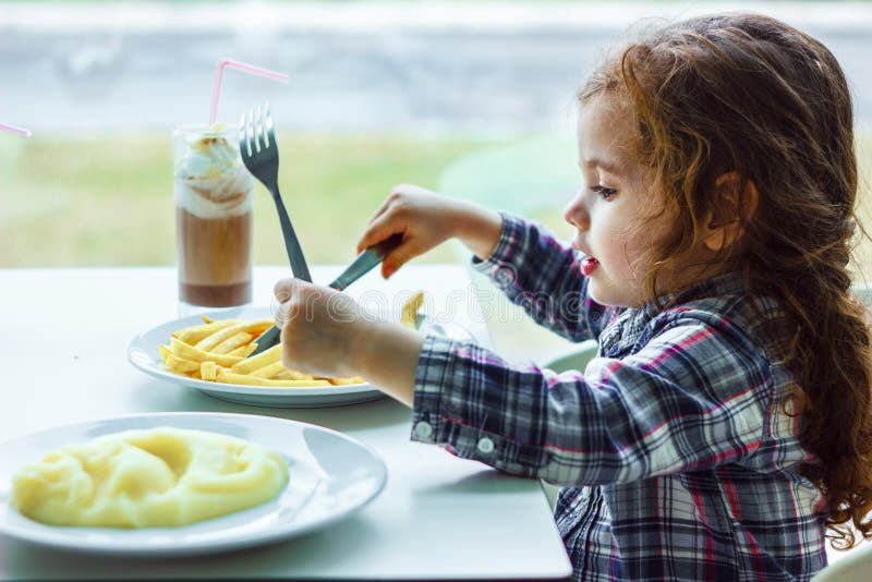 Little Girl Having Lunch in the Restaurant with the Table Knife and ...