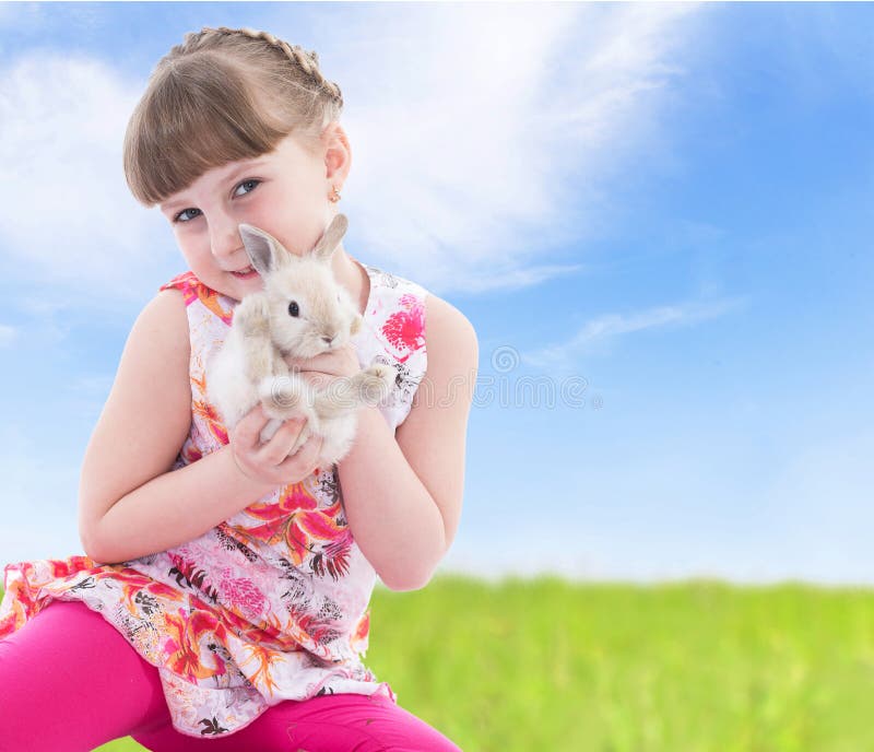 Little Girl Holding a Rabbit Sitting on Meadow. Stock Image - Image of ...