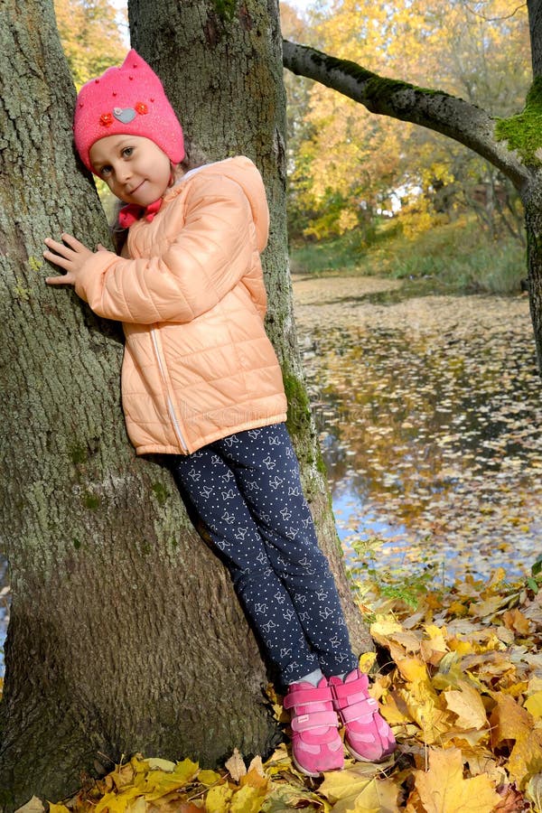Little Girl is Leaning on a Tree by the Pond in Autumn Park Stock Photo ...