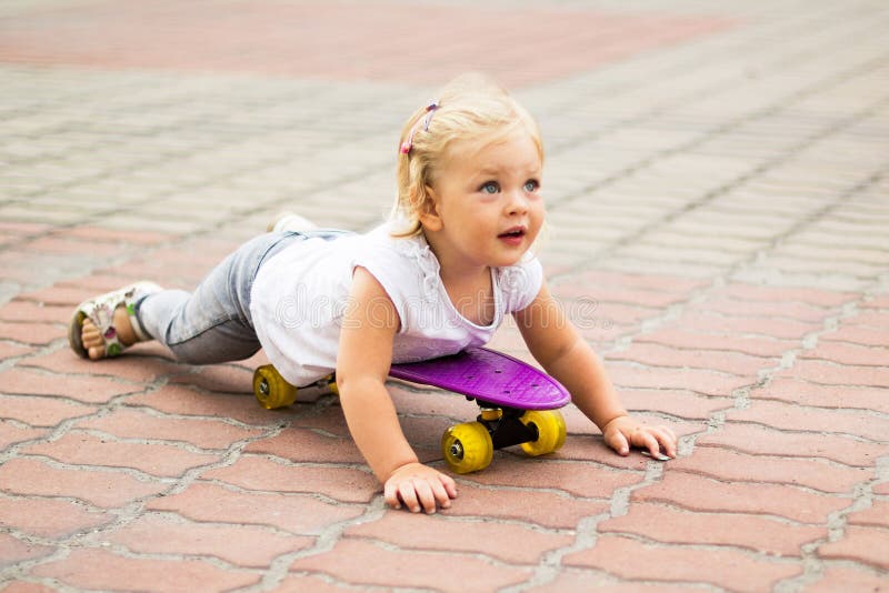 A Little Girl is Lying on a Skateboard. he Studies To Ride Stock Image ...