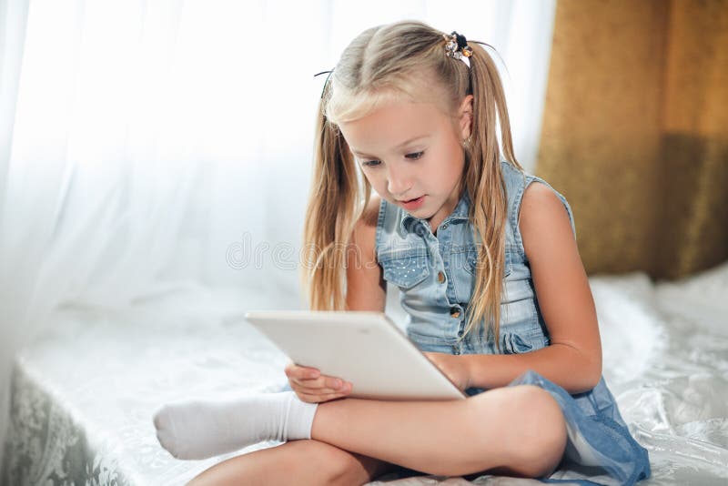 Cute Little Girl Playing with Tablet. Happy Blondy Girl at Home. Funny ...