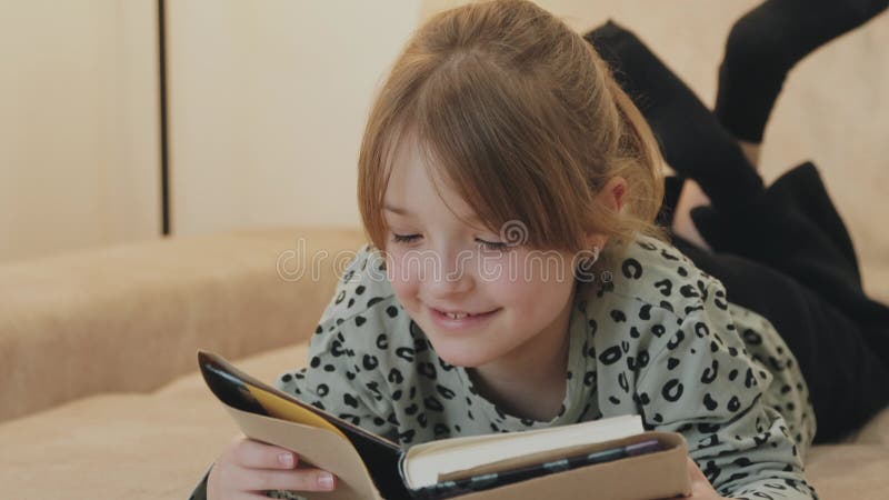 Little Girl Reading a Book on the Sofa, Expressing Different Emotions ...
