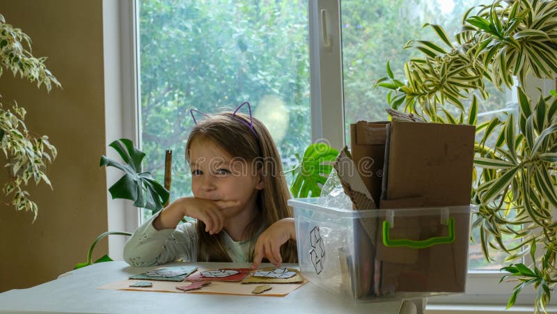 Little Girl Sits at a Table Against the Background of a Window with ...
