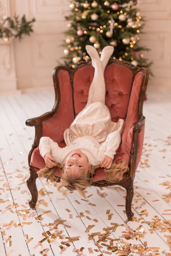 A Little Girl Sits Upside Down in a Chair. a Hyperactive Child Stock ...
