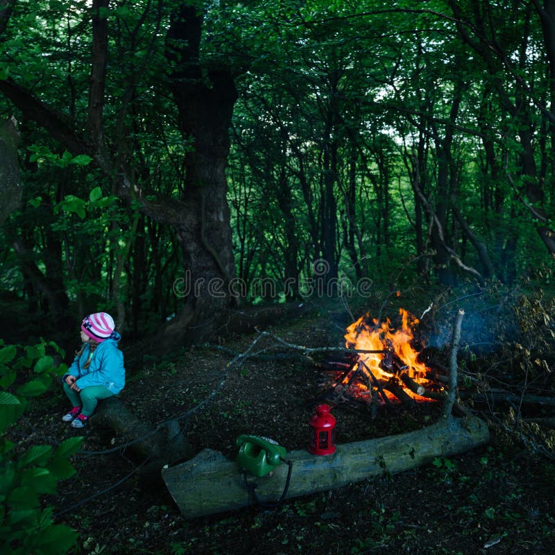 A Little Girl Sitting by the Fire in the Forest. Stock Photo - Image of ...
