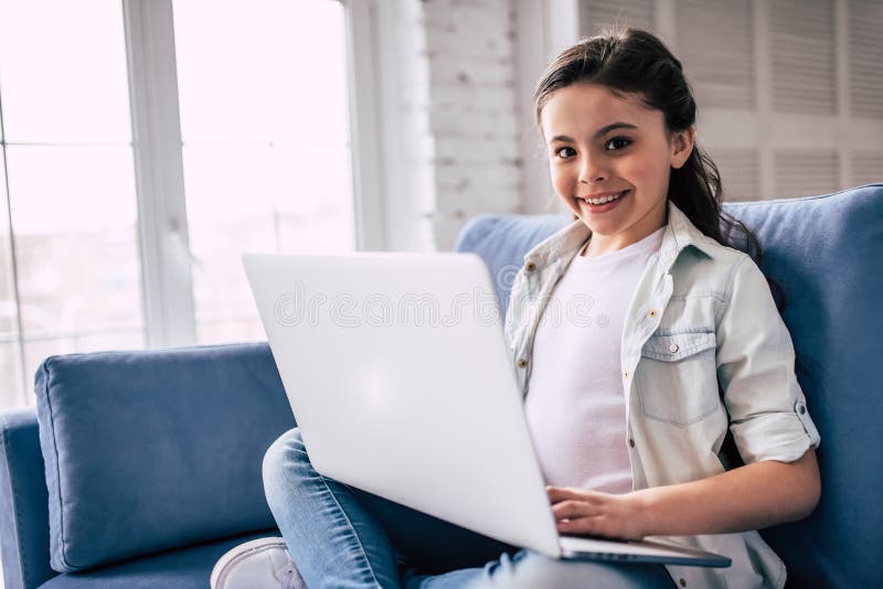 The Little Girl Sitting on the Sofa with a Laptop. Stock Image - Image ...