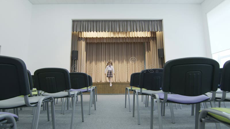 A Little Girl Goes To the Stage in an Empty Hall without People. Stock ...