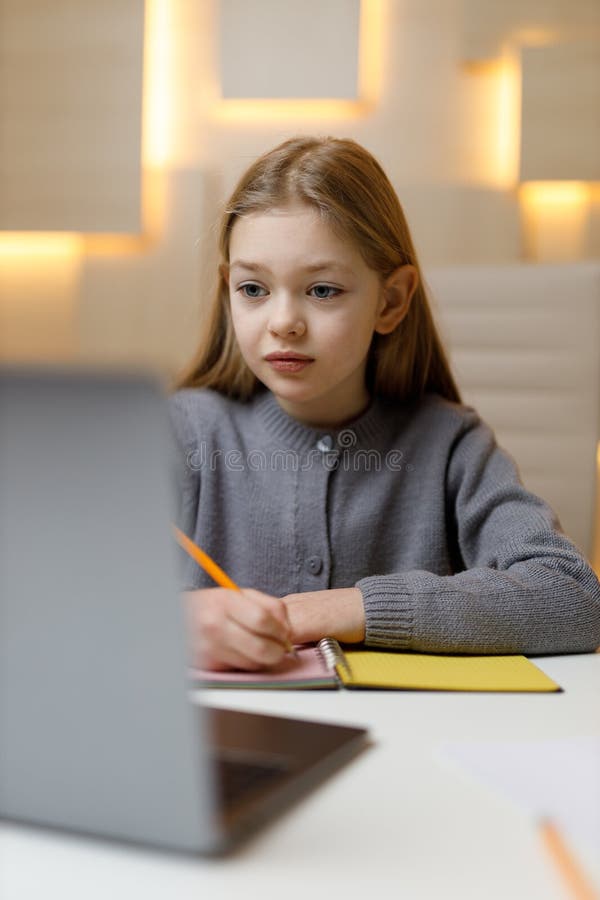 A Little Girl is Studying Remotely on a Desktop Behind a Laptop Stock ...