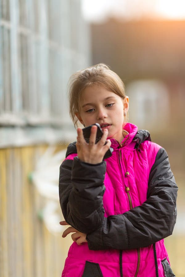 Little Girl is Typing on Smartphone Standing Outdoors. Happy. Stock ...