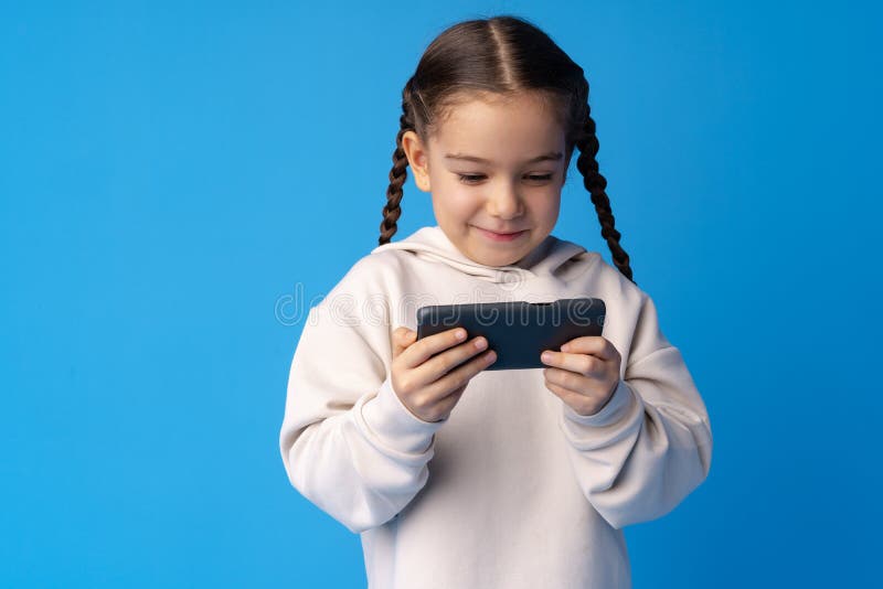 Little Girl Using Mobile Phone.against Blue Background Stock Photo ...