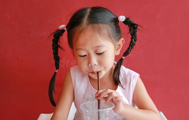 Little Girl Using Straw To Drink Water from Plastic Cup in the ...