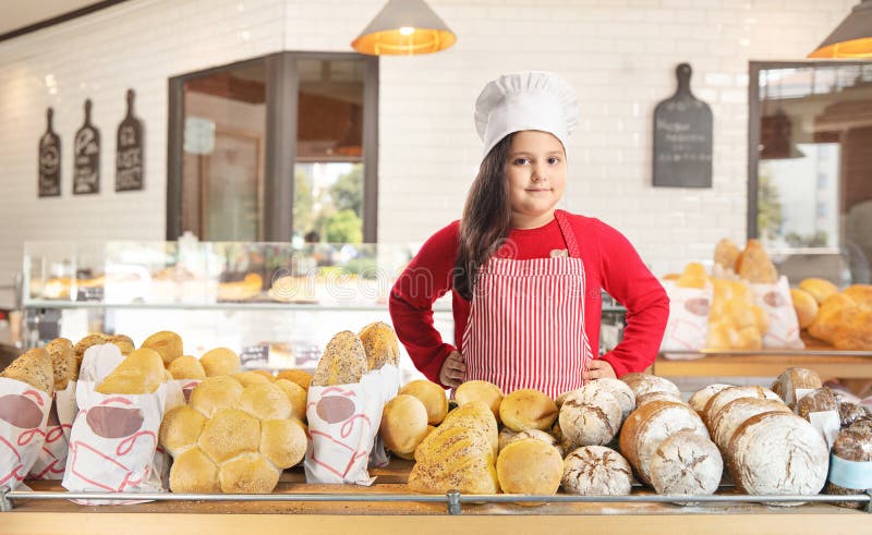 Little Girl Wearing Apron and Cooking Hat in a Bakery Stock Image ...