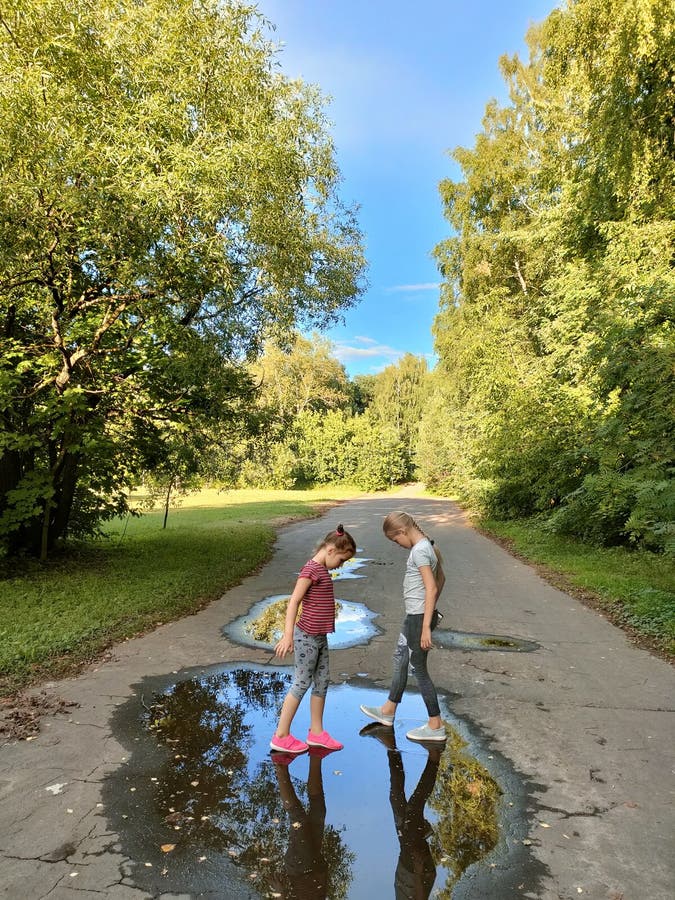 Little Girls Walk on the Road in a Puddle Stock Photo - Image of puddle ...