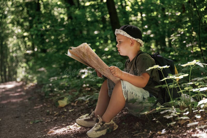 Little Kid Tourist is Sitting and Reading the Map in the Forest Stock ...