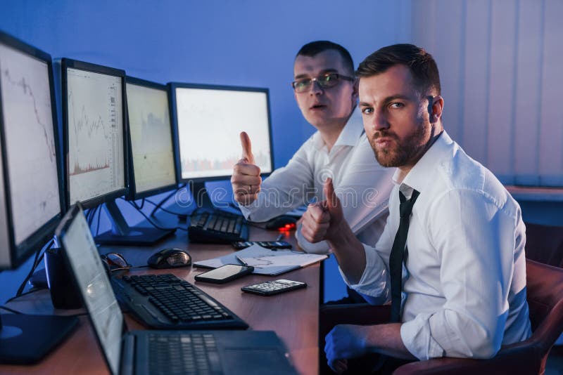 Little Laptop is on the Table with Many Screens. Two Stock Traders ...