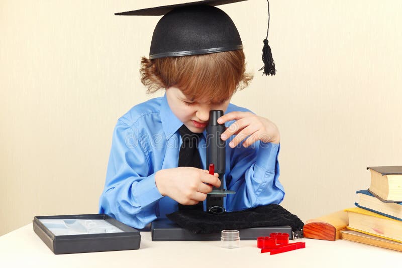 Little Smart Boy in Academic Hat Looking through Microscope at His Desk ...