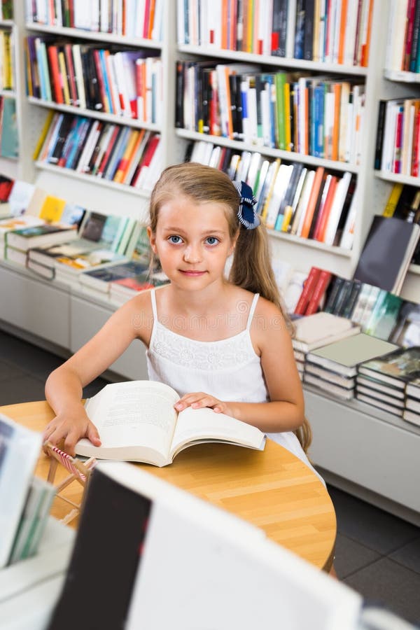 Little Smart Girl Reading a Book in the School Library Stock Photo ...