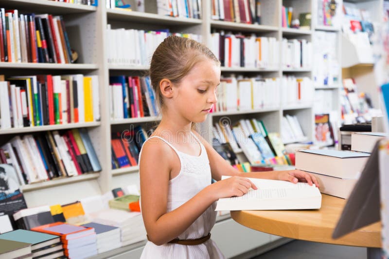 Little Smart Girl Reading a Book in School Library Stock Image - Image ...