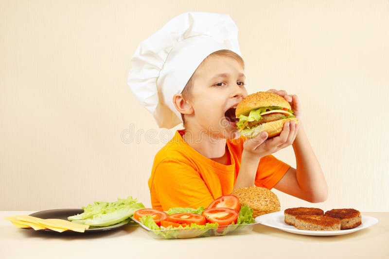 Little Smiling Boy in Chefs Hat is Tasting Cooked Hamburger Stock Photo ...