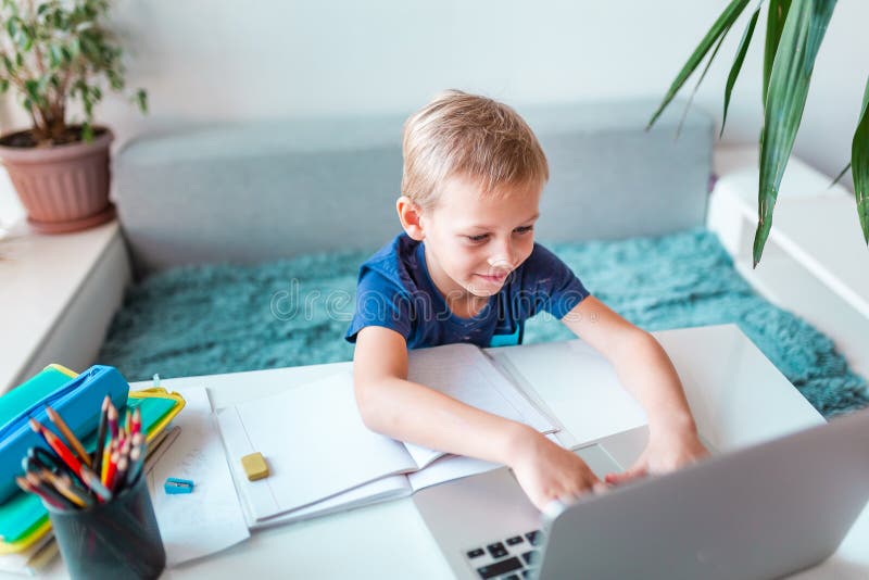Little Young School Boy Working at Home with a Laptop and Class Notes ...