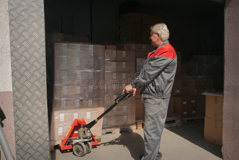 A Loader Rolls a Trolley in a Warehouse among Many Boxes Stock Photo ...