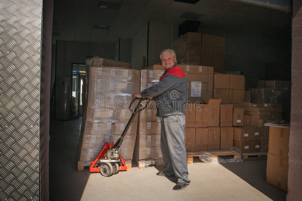 A Loader Rolls a Trolley in a Warehouse among Many Boxes Stock Image ...