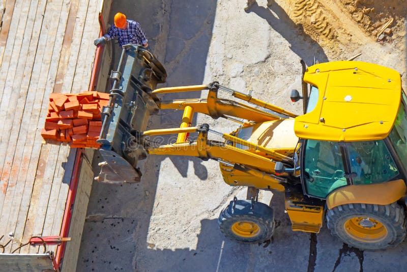 Loading Bricks into the Cargo Body of a Truck Using a Tractor with a ...