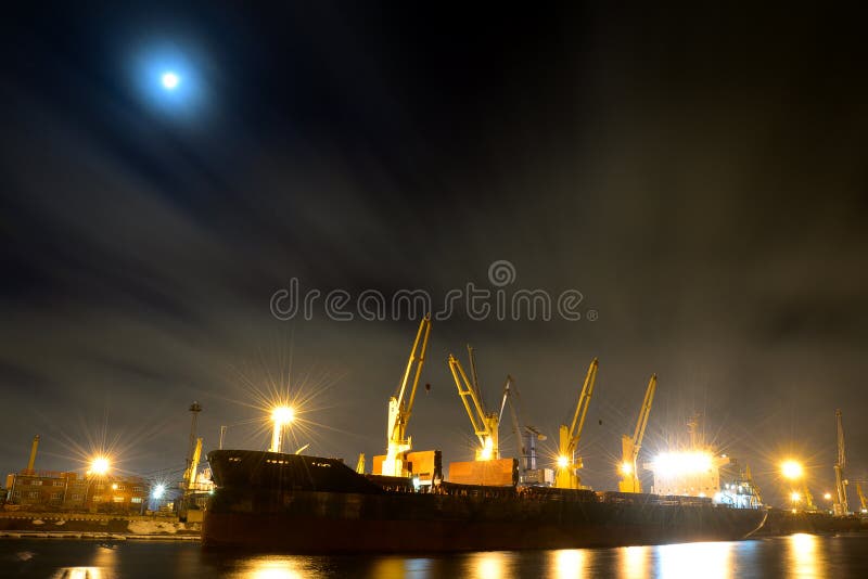 The Loading Cargo Ship with Cranes is Moored in Port at Night Stock ...
