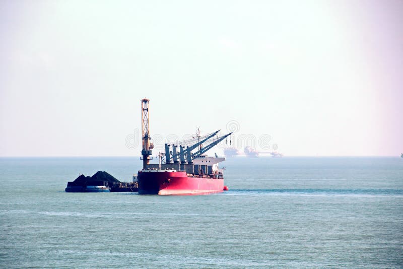 Loading Coal from Cargo Barges Onto a Bulk Carrier Using Ship Cranes ...